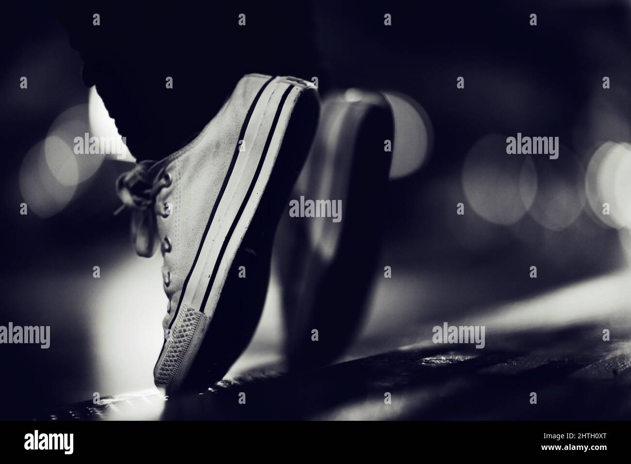 Going over the edge. Cropped image of a person wearing sneakers ...