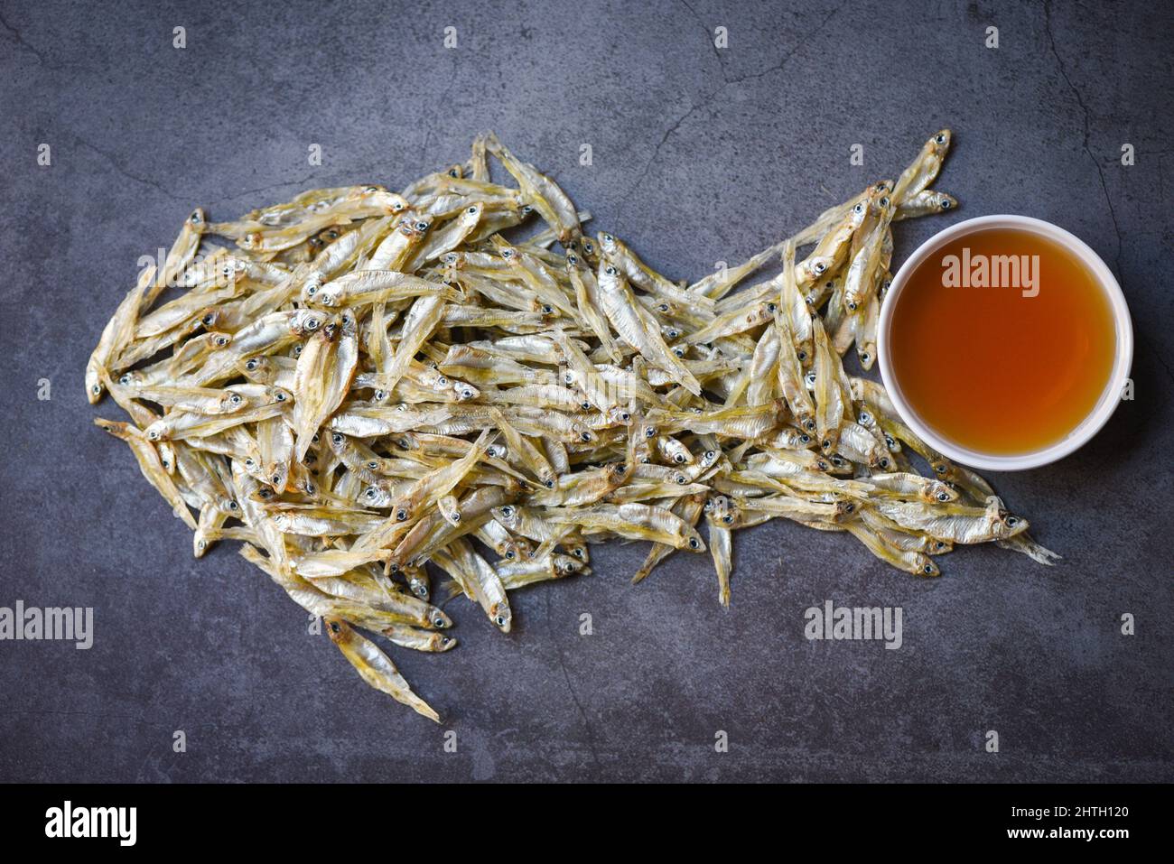 fish sauce on white bowl and small dried fish on dark background, fish ...