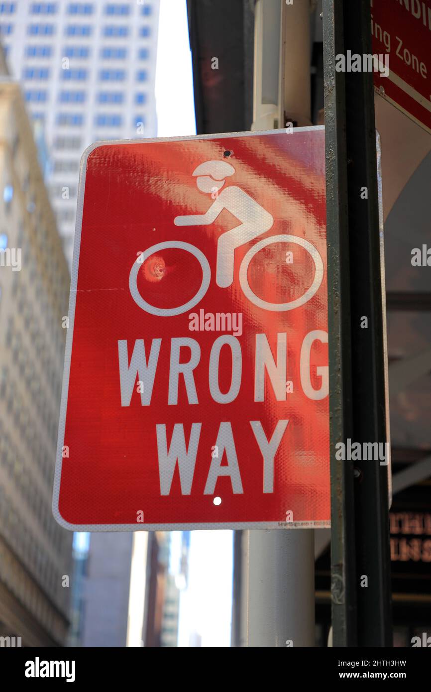 A red warning sign of wrong way for bicycle by the sidewalk on midtown ...