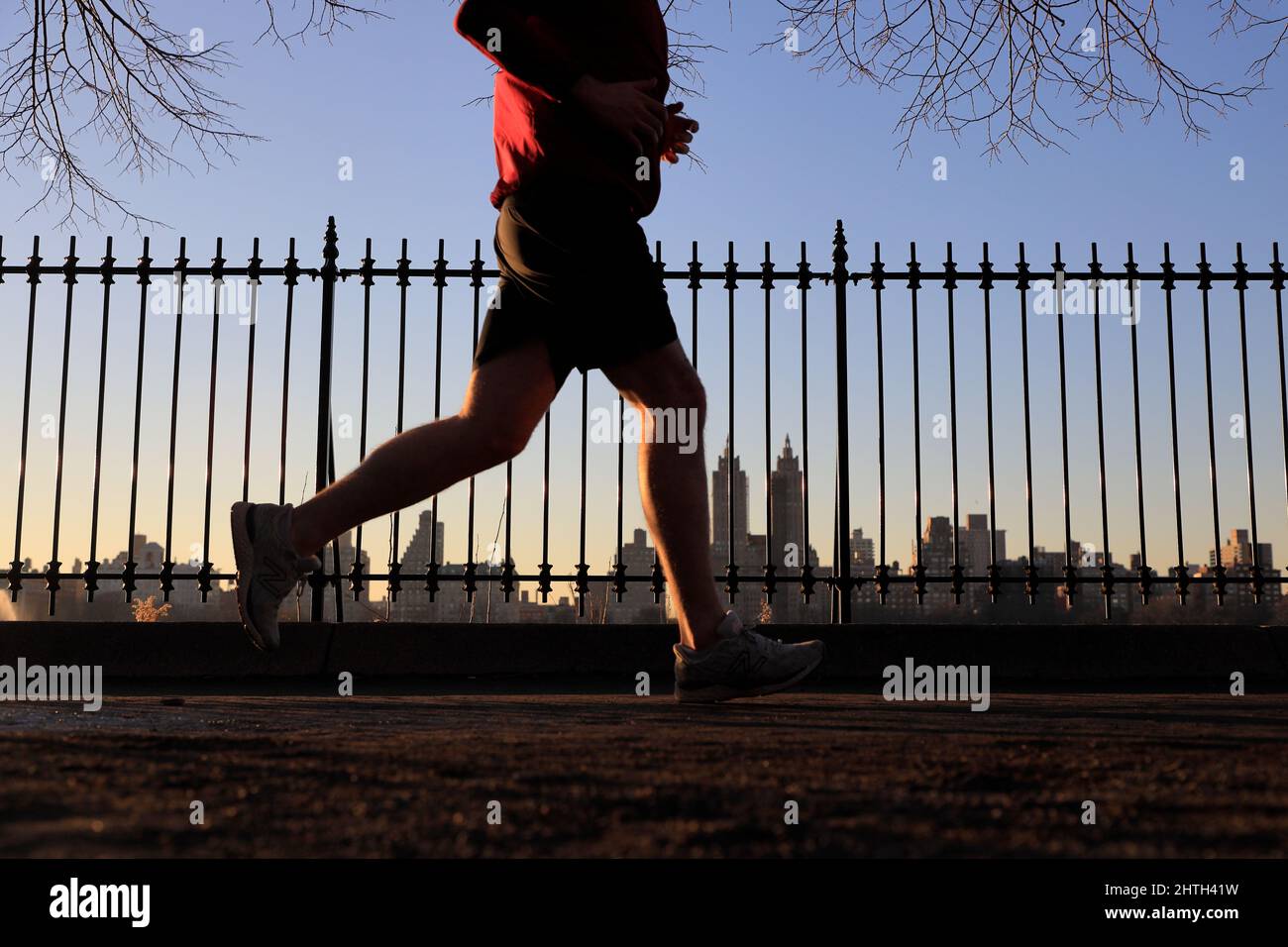 Man running alone the path of Central Park Reservoir with the skyline ...