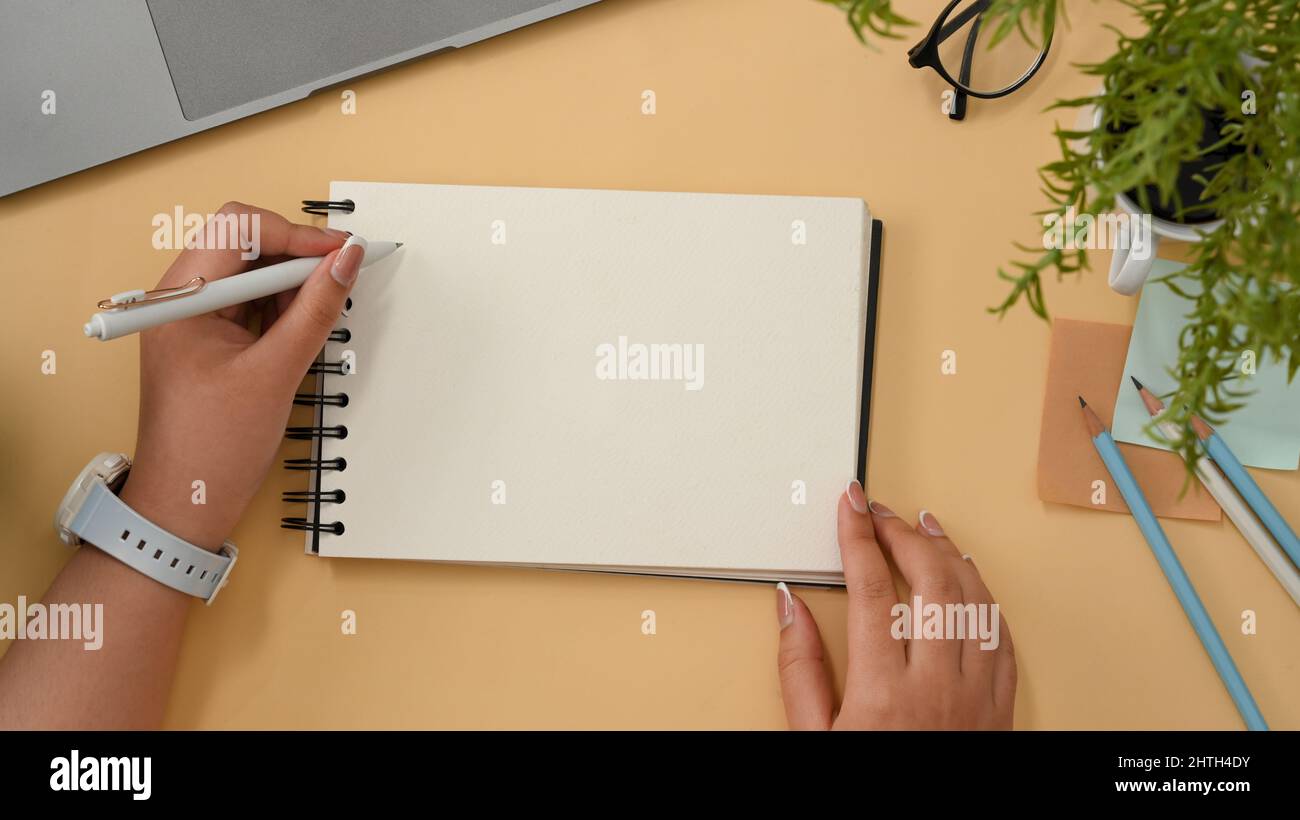 Female university student taking notes on spiral notepad, writing a ...