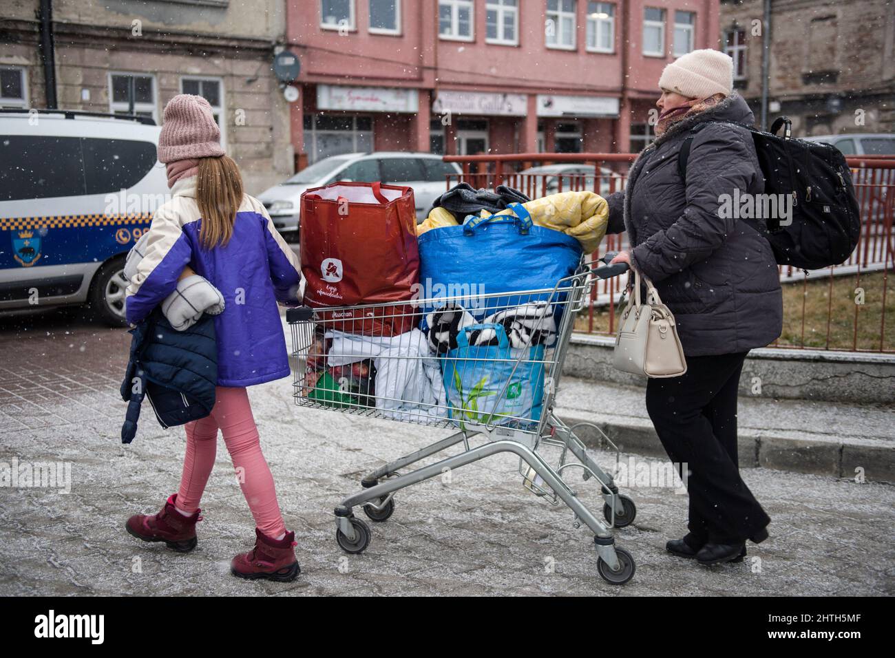 Refugees are seen carrying their belongings in a shopping cart while ...
