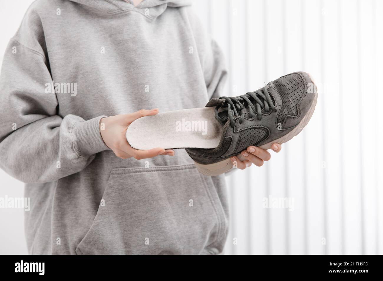 Woman putting orthopedic insole into shoe at home. Sports girl fitting ...