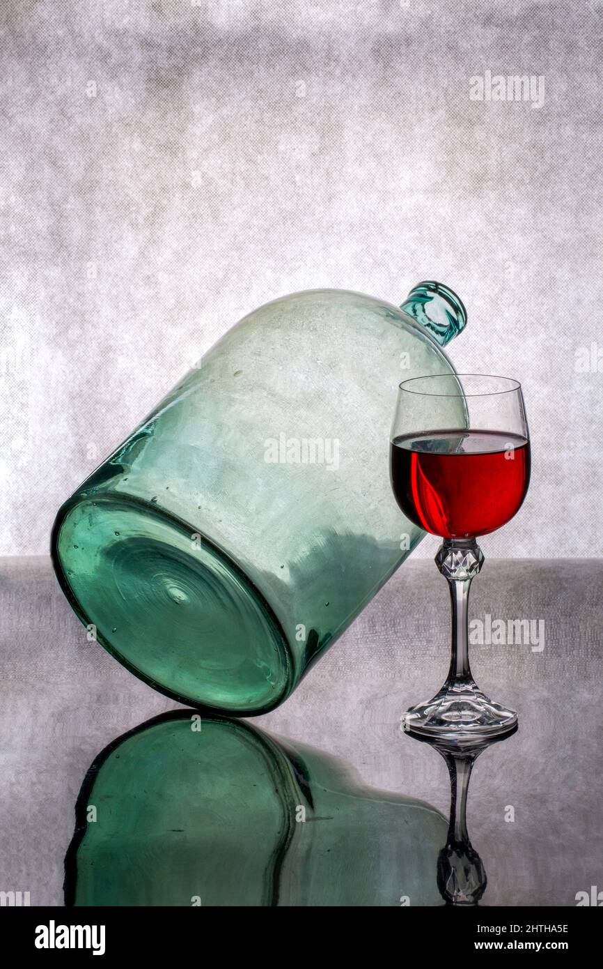 Still life with a tilted glass jar and a glass of red wine Stock Photo ...