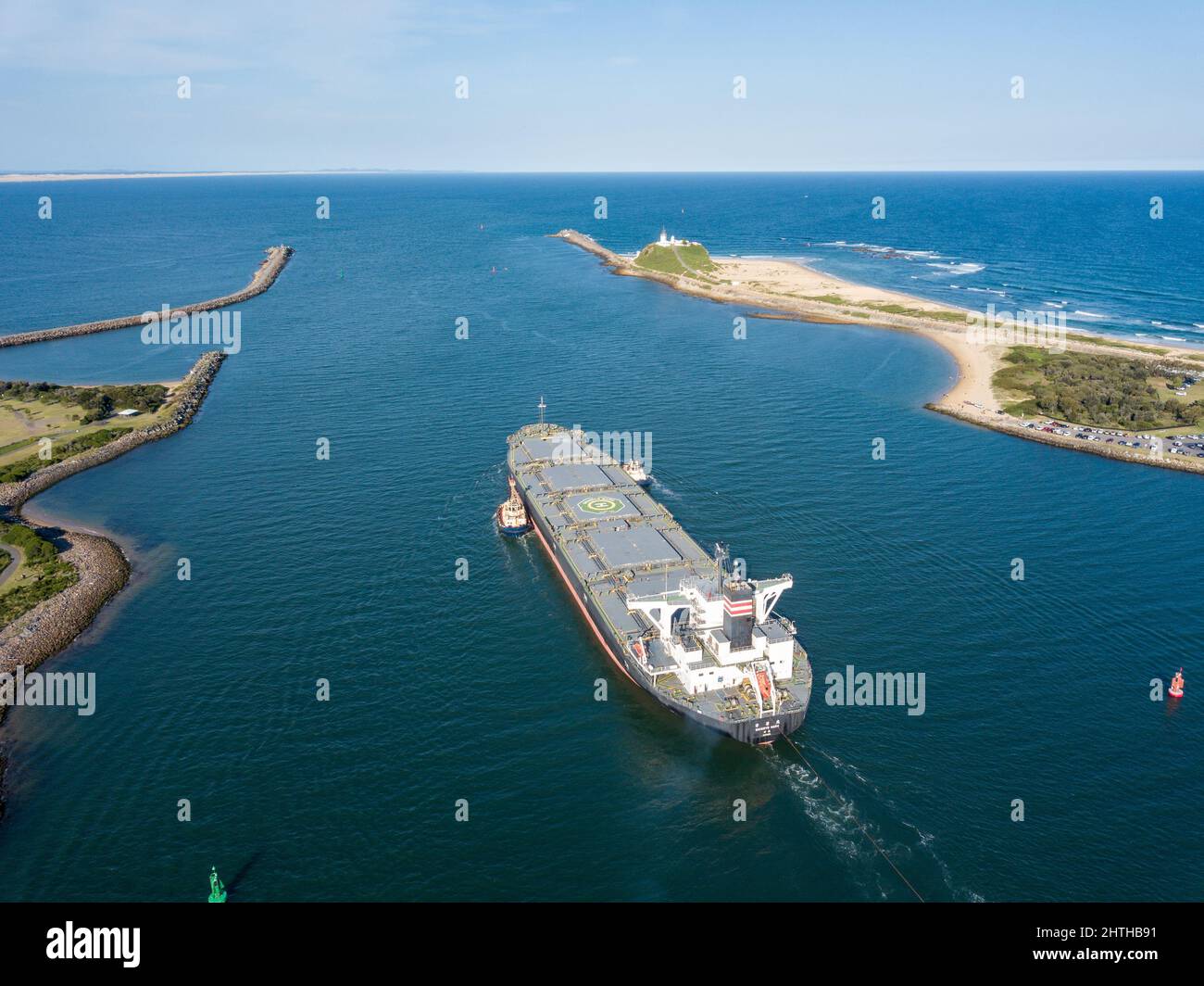 Aerial view of a cargo ship being tagged with small boats near a harbor ...