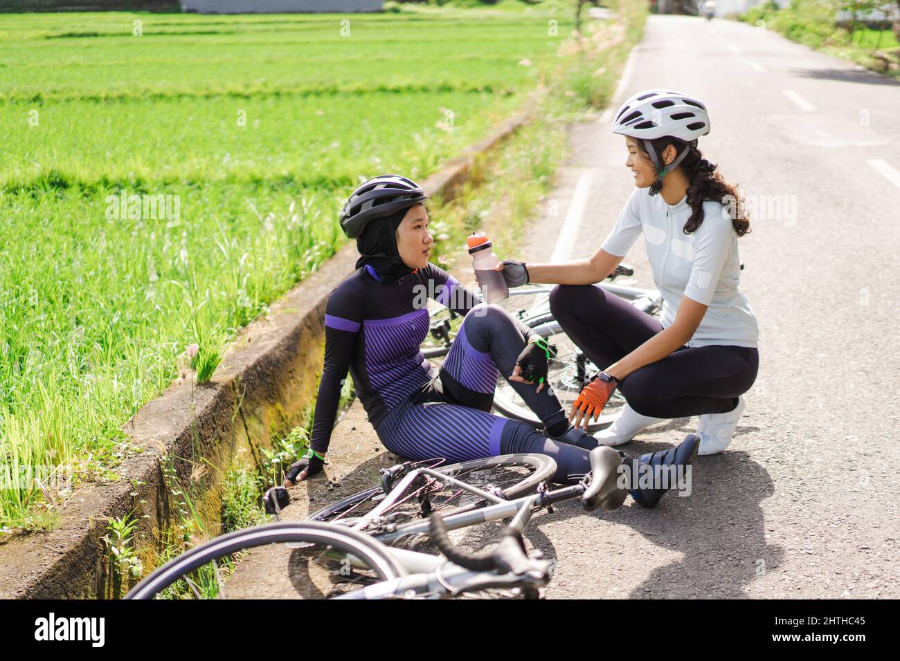 woman cyclist giving a bottle of water to her friend's Stock Photo - Alamy