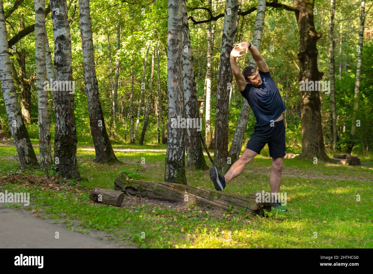 A young enduring athletic athlete is doing stretching in the forest ...