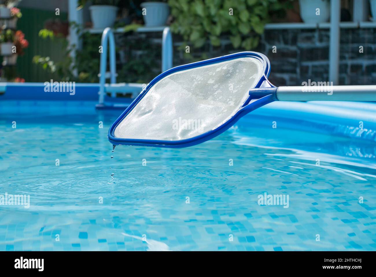 Swimming pool cleaning net with water droplets in the background of ...