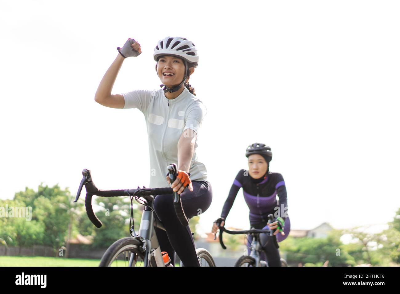 excited young woman riding her road bike with friend Stock Photo - Alamy