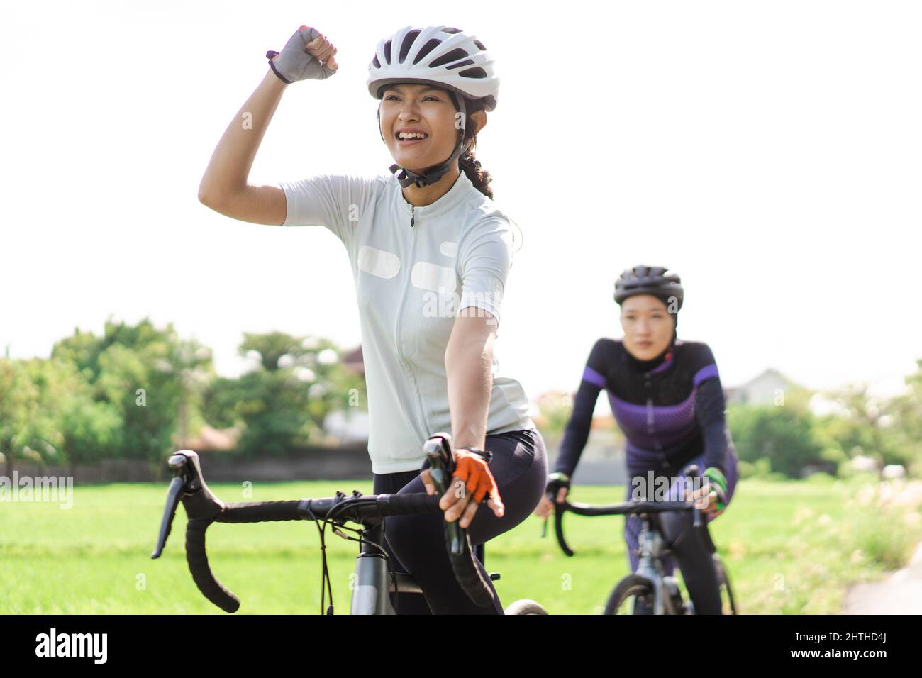 excited young woman riding her road bike with friend Stock Photo - Alamy