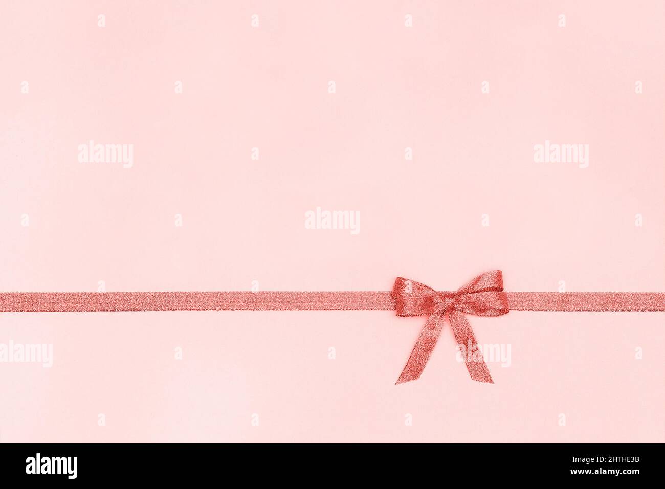 Decorative shiny ribbon with bow on pastel pink background with copy ...