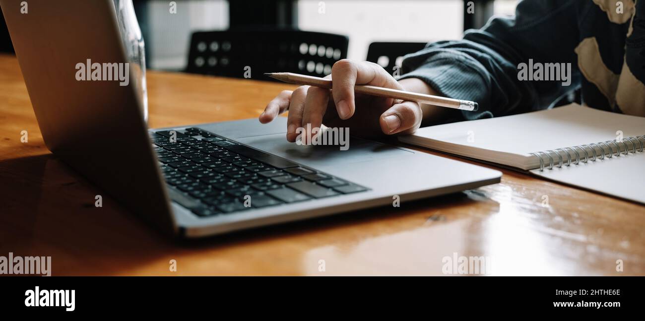 Cropped photo of asian woman using laptop and writing making list ...