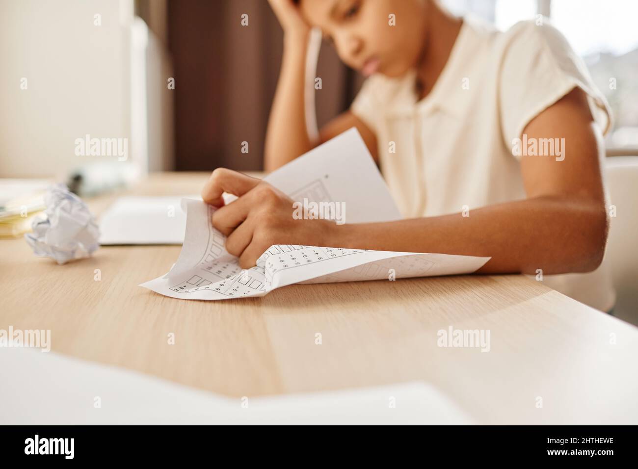 Close up of anxious child crumpling homework while struggling with ...