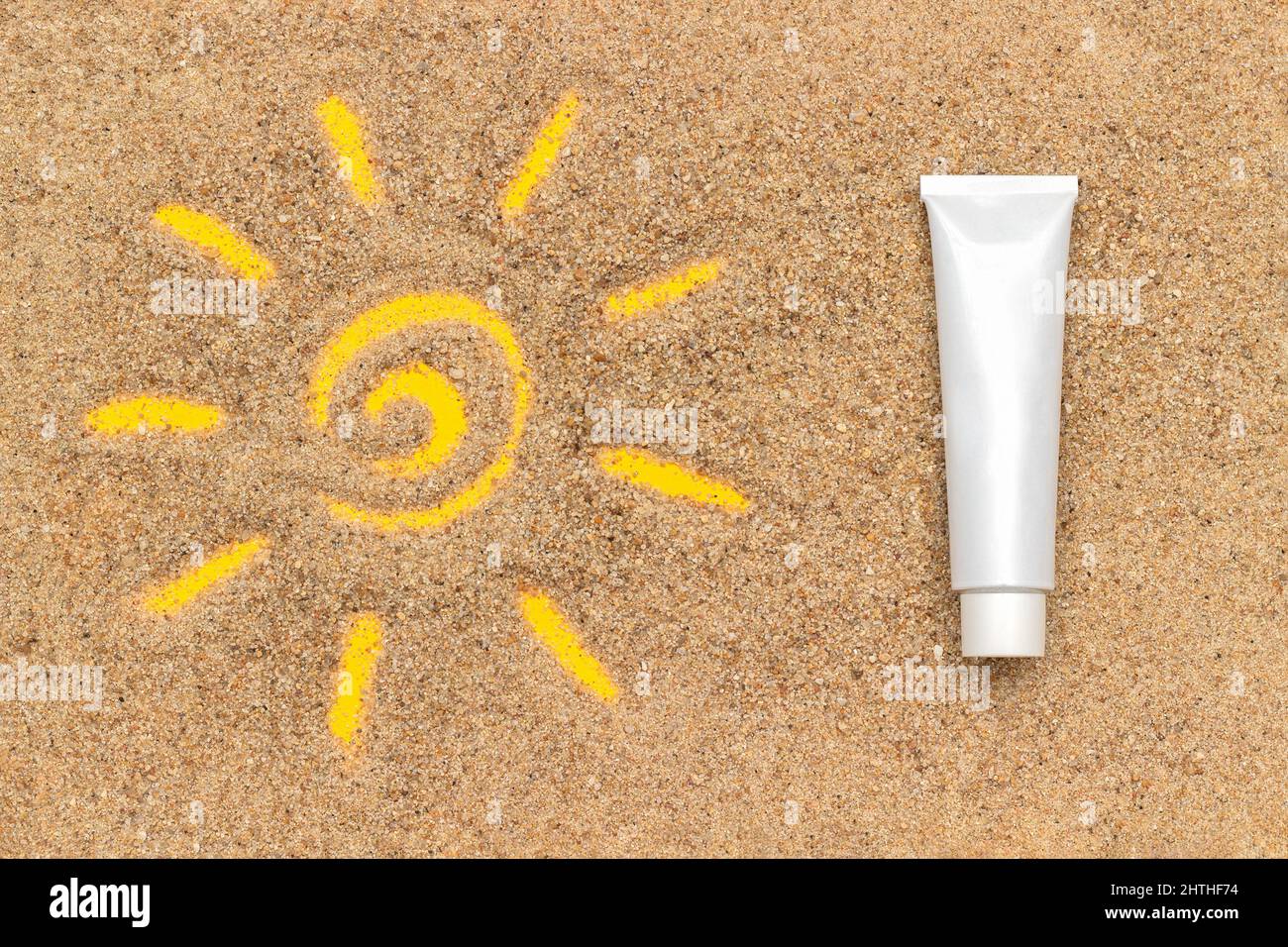 Sun sign drawn on sand and white tube of sunscreen. Template mockup for ...