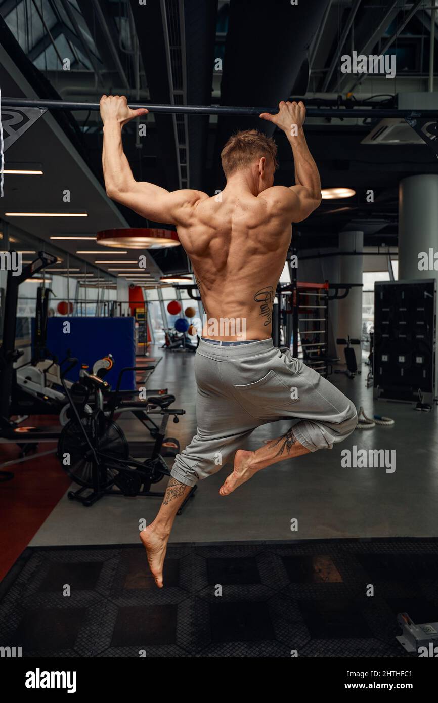 Muscular strong man exercising in the sport gym, Man doing horizontal push-ups with bars in gym ...