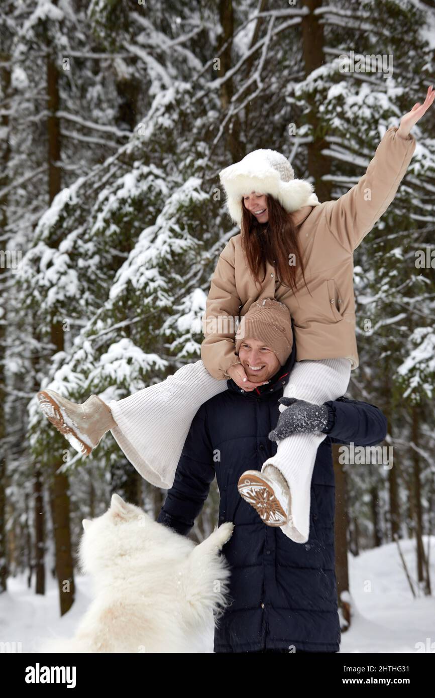 Happy young couple in winterwear playing with purebred siberian husky ...
