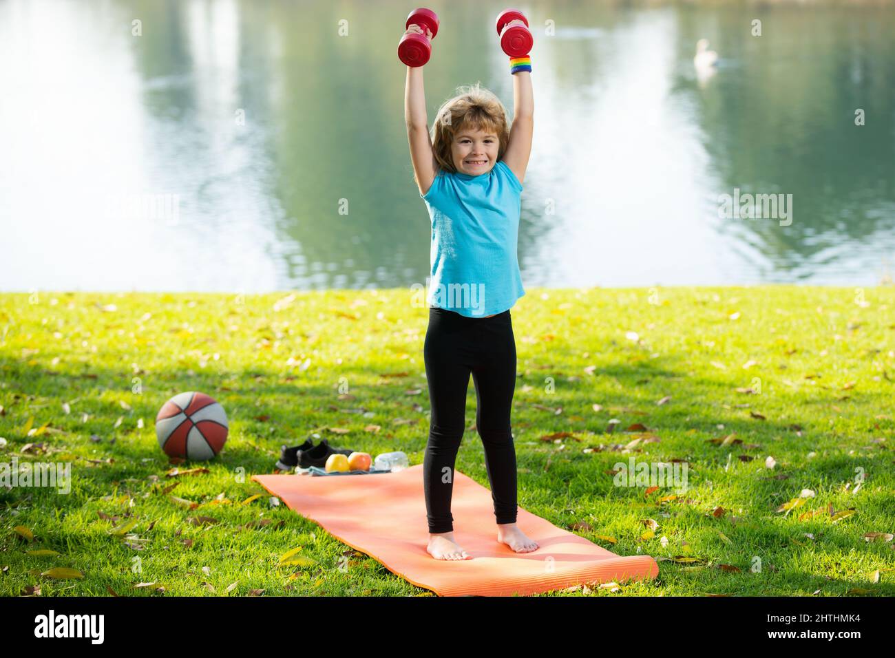 Kids sport. Cute little boy doing exercises with dumbbells in green ...