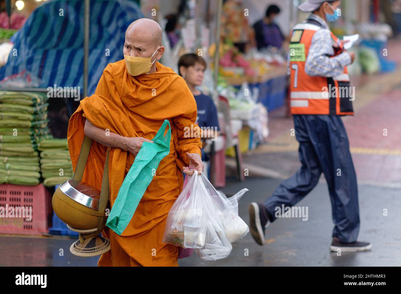 A monk in a street in Bangkok, Thailand, carrying his alms bowl and his ...