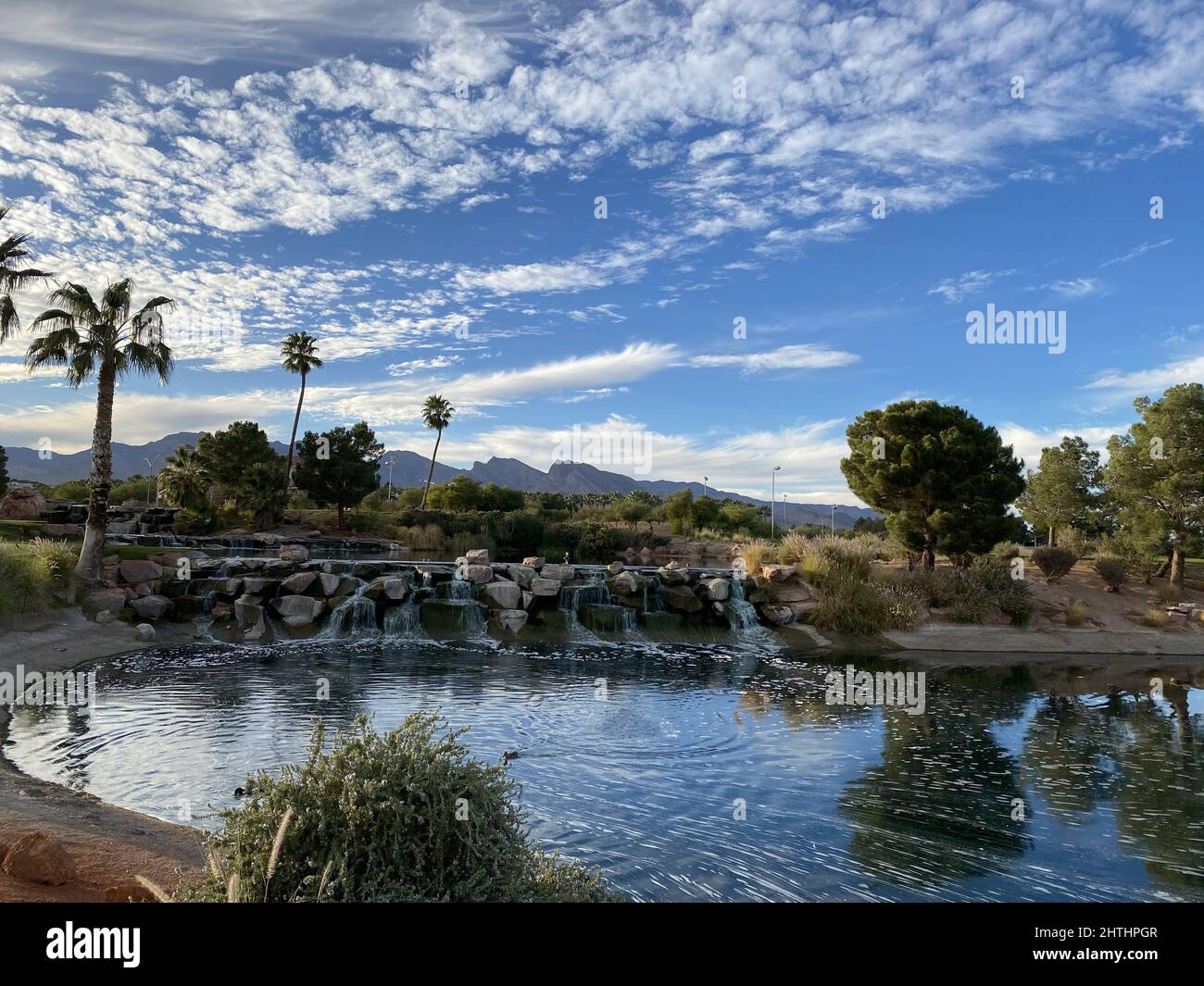 Small waterfall and pond surrounded by trees under the blue sky Stock ...