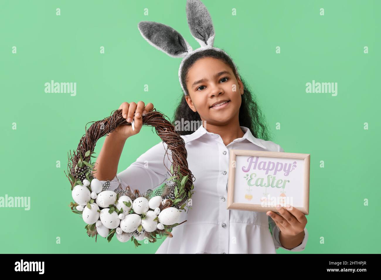 Cute African-American girl with bunny ears, greeting card and Easter ...