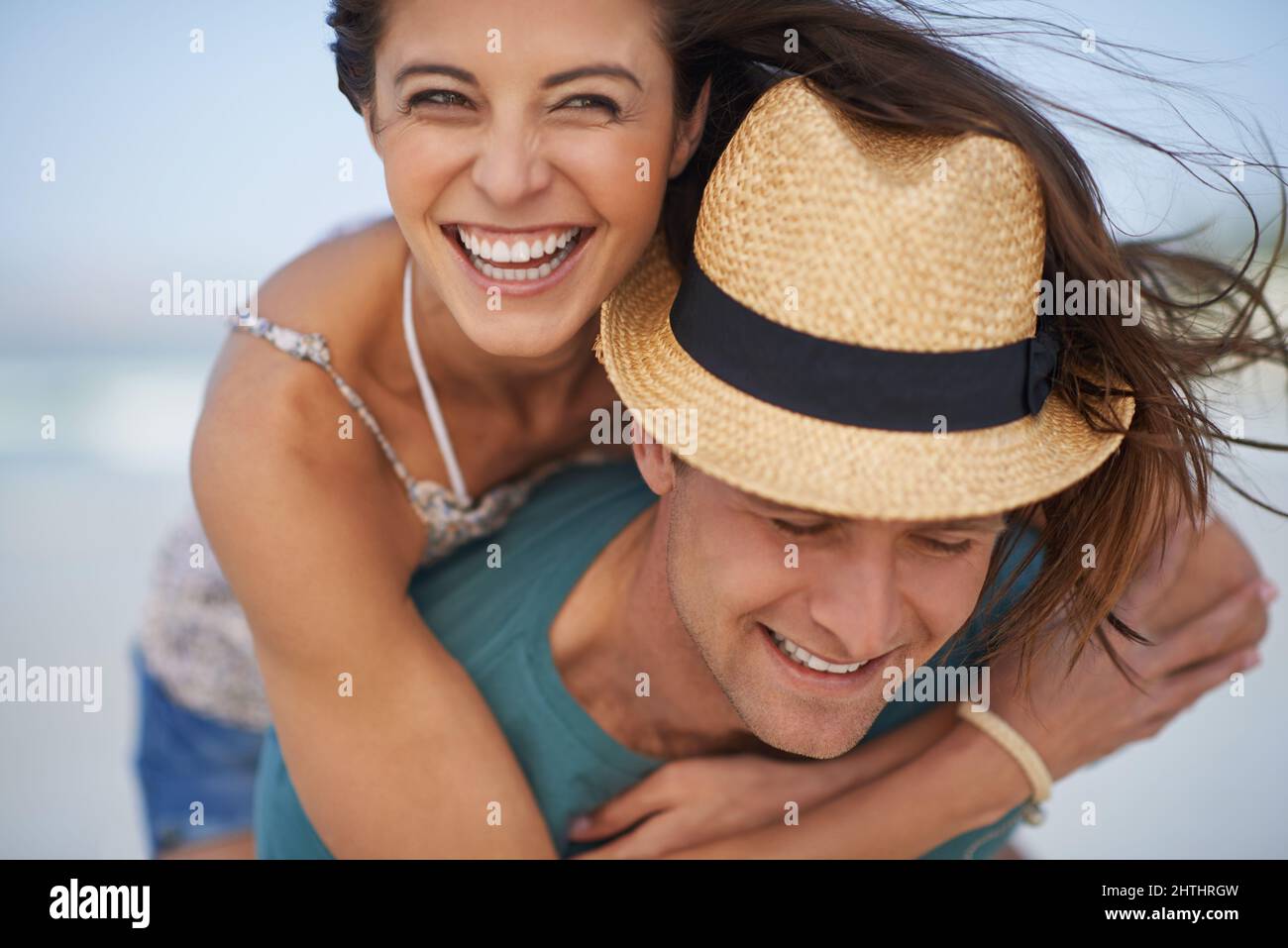 They always have fun together. A young couple piggybacking at the beach ...
