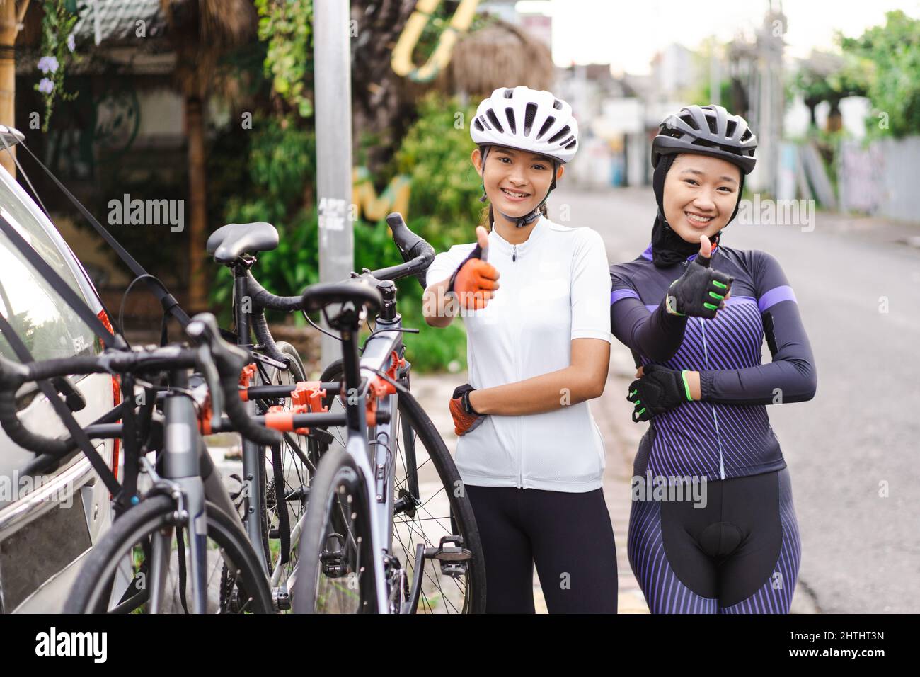 two muslim female cyclist with their road bicycle on a rack thumb up ...