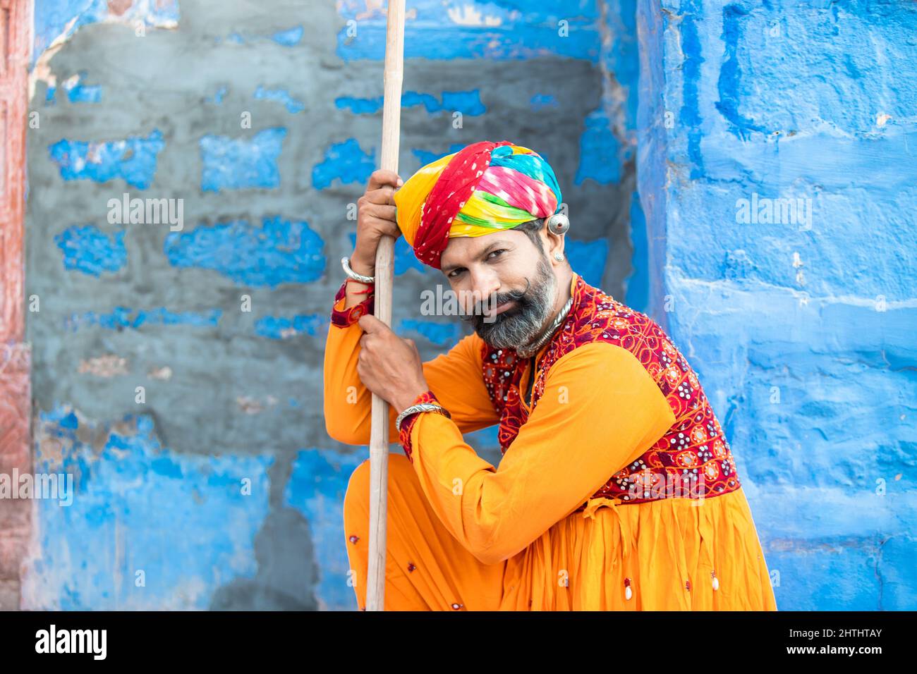 Happy traditional north indian man wearing colorful attire holding wood ...