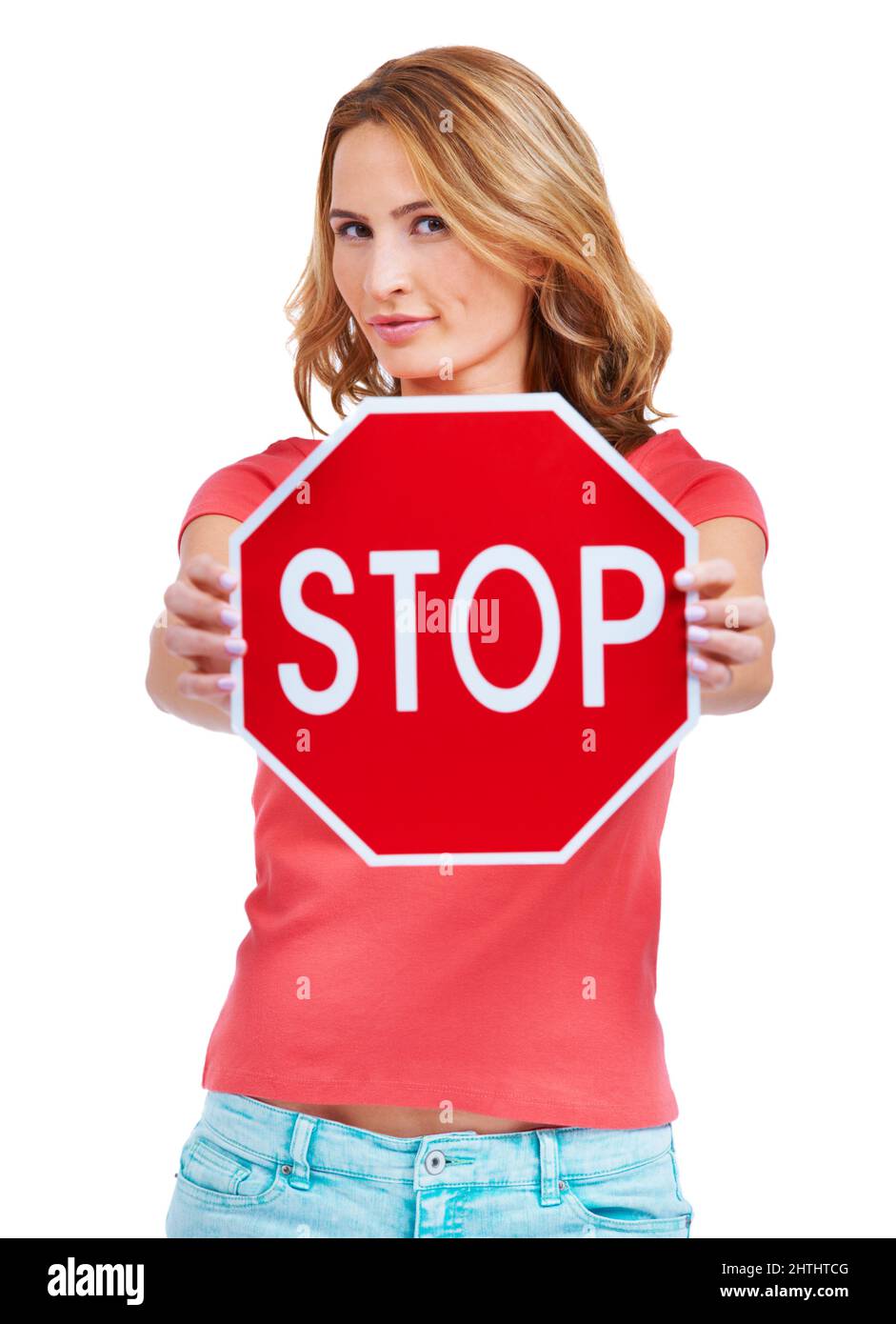 Stop. A young woman holding a stop sign against a white background ...