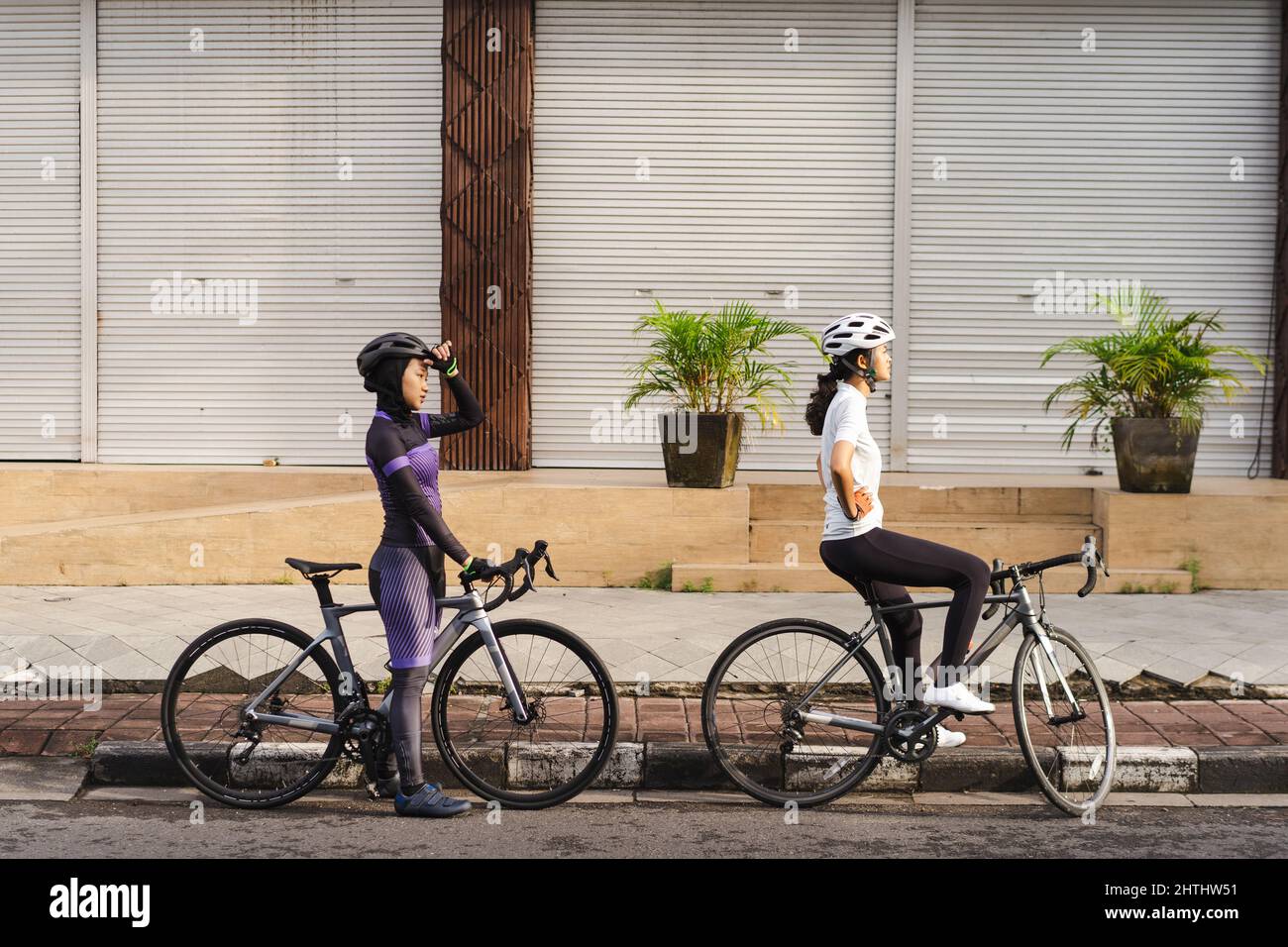 beautiful friend riding a bicycle together and take break on a roadside ...
