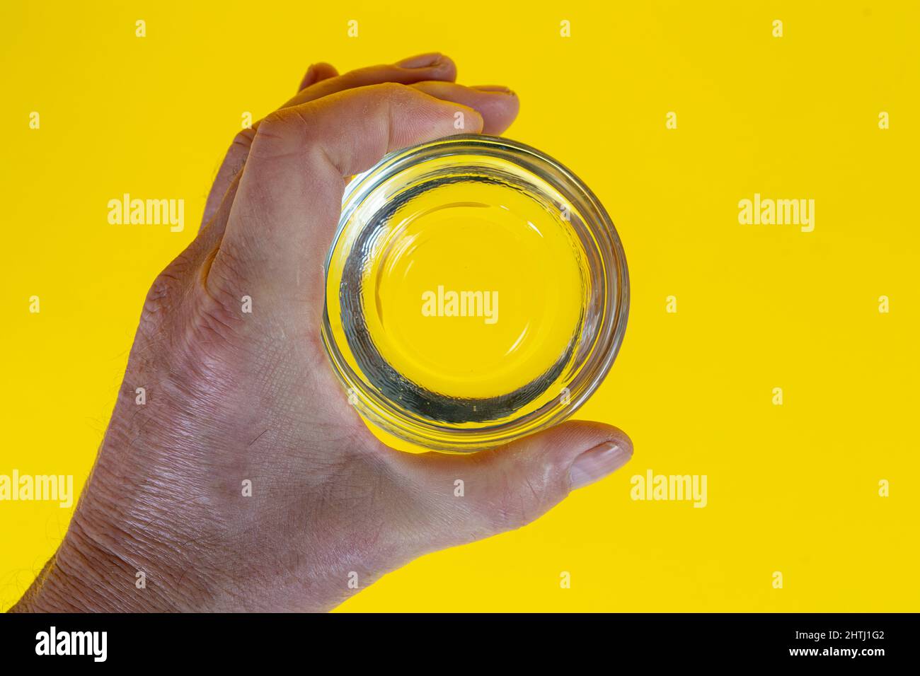 a glass beaker in hand viewed from above with a yellow background Stock ...