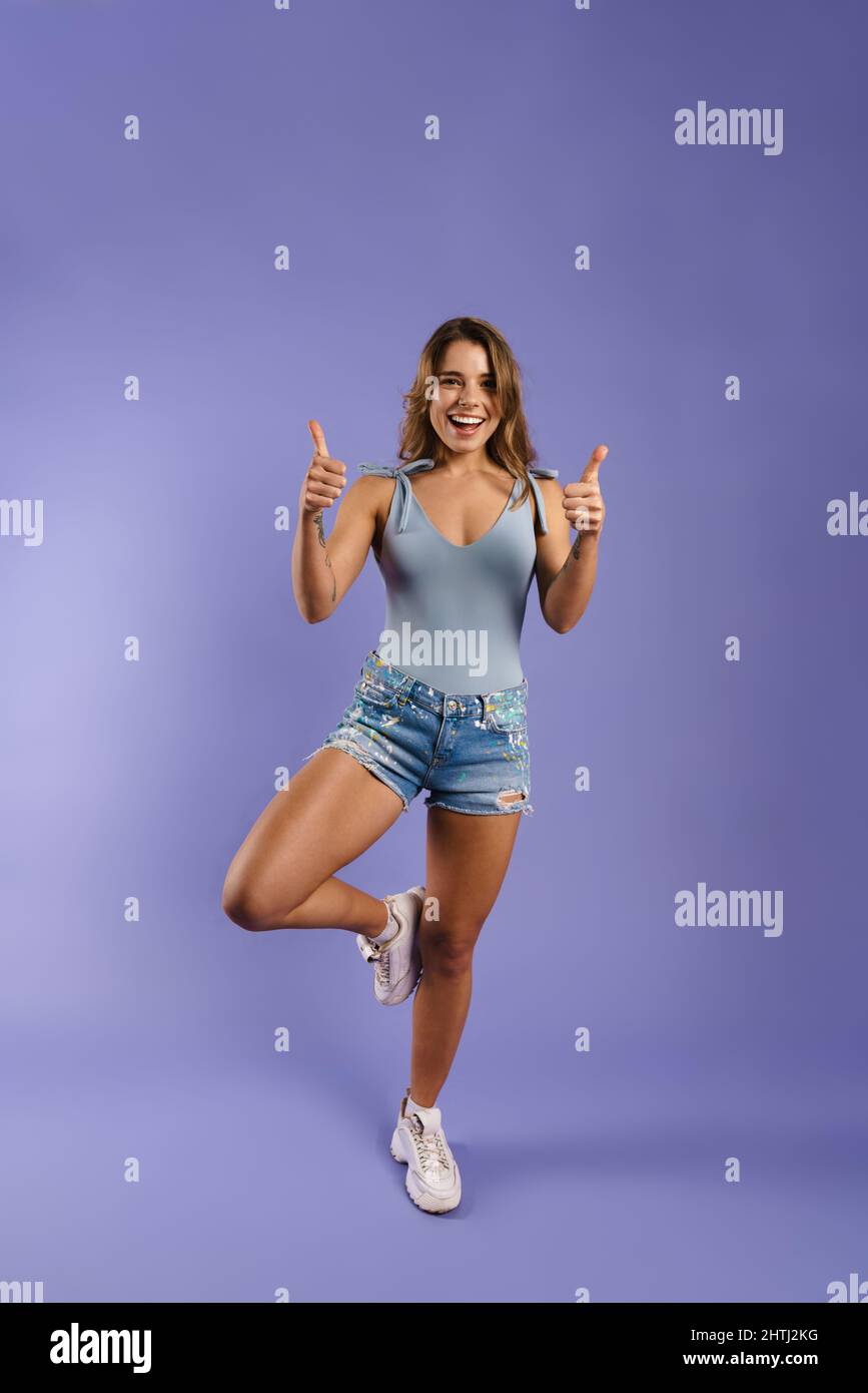 Happy young white woman wearing denim shorts standing isolated over ...