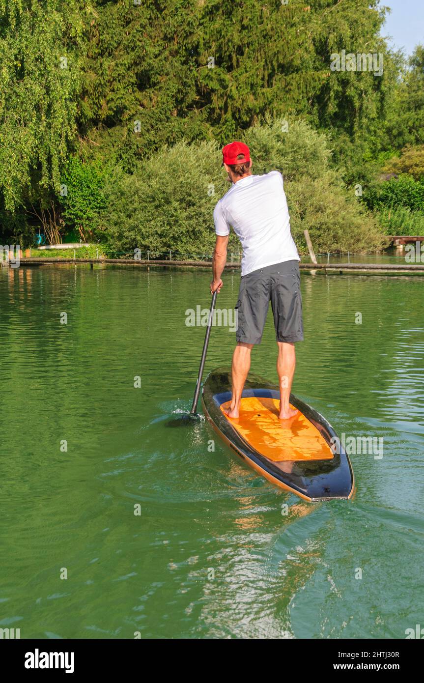 Sporty man doing a morning workout with SUP board on a beautiful lake ...