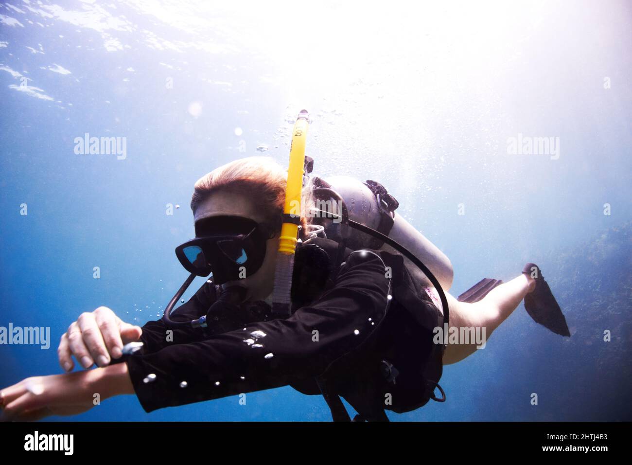 Time to descend. Young female scuba diver floating through the water as ...
