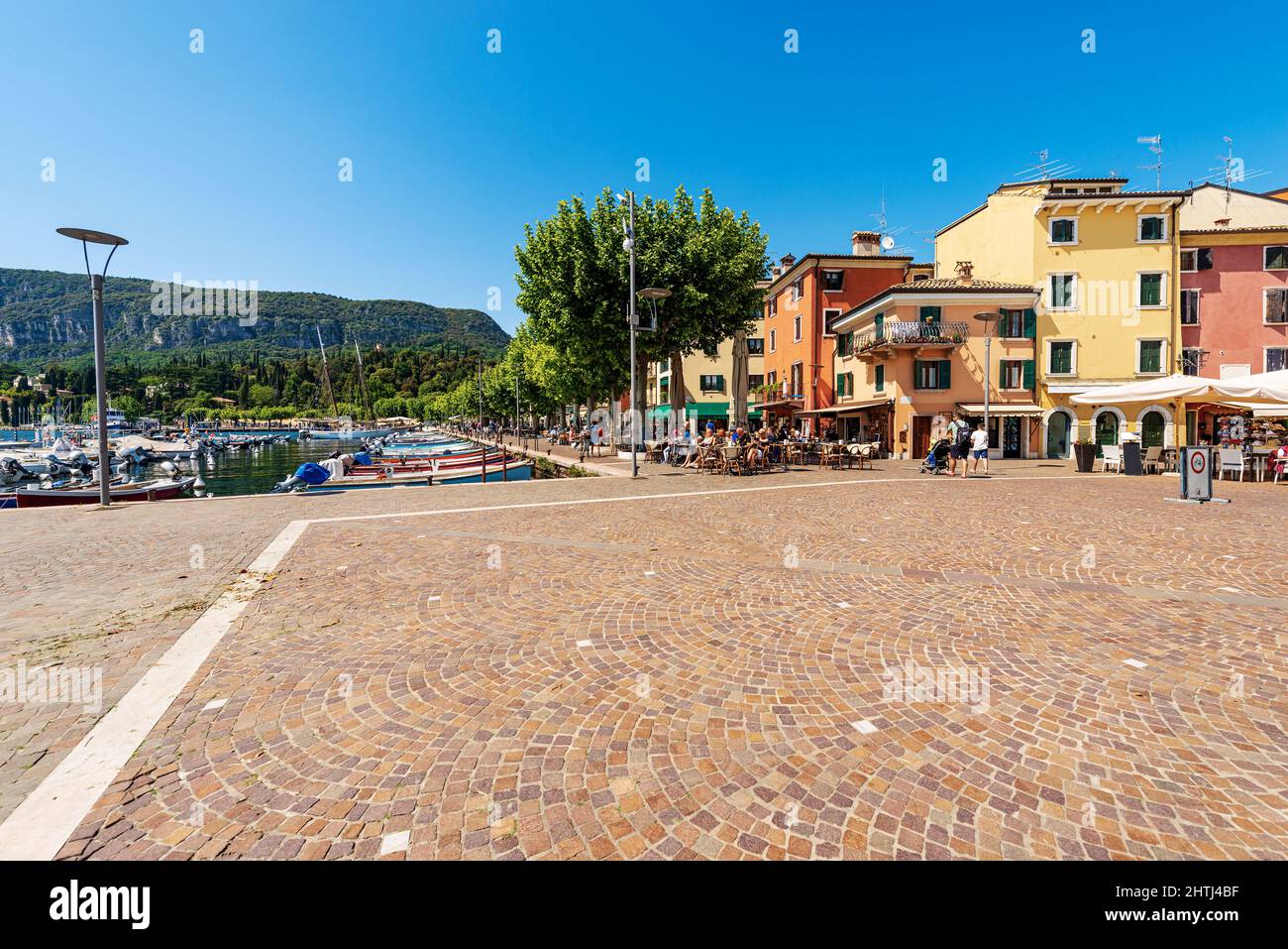 Downtown of Garda village. Outdoors restaurants in front of the port of ...