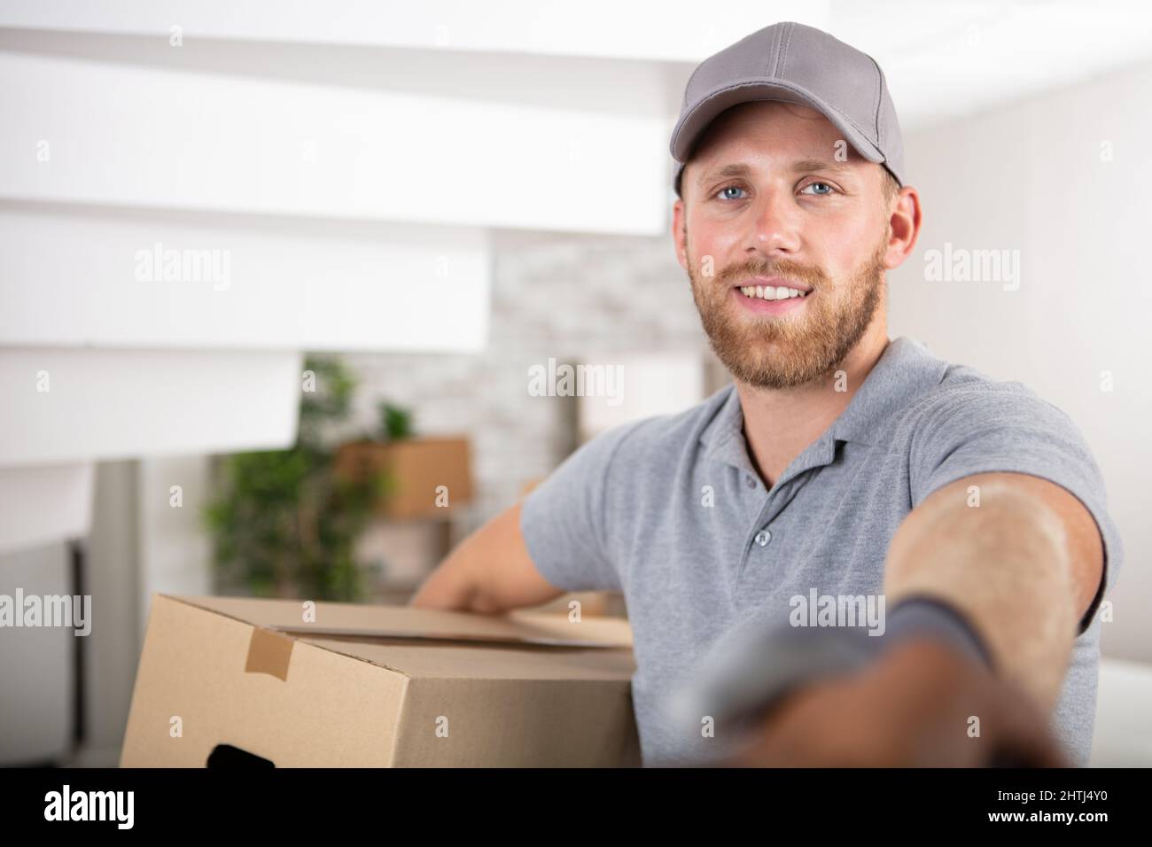smiling young delivery man holding a cardboard box Stock Photo - Alamy