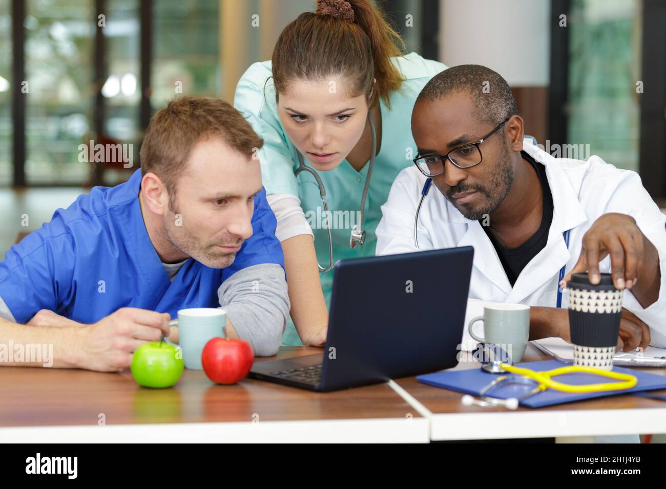 medical team huddle around laptop Stock Photo - Alamy