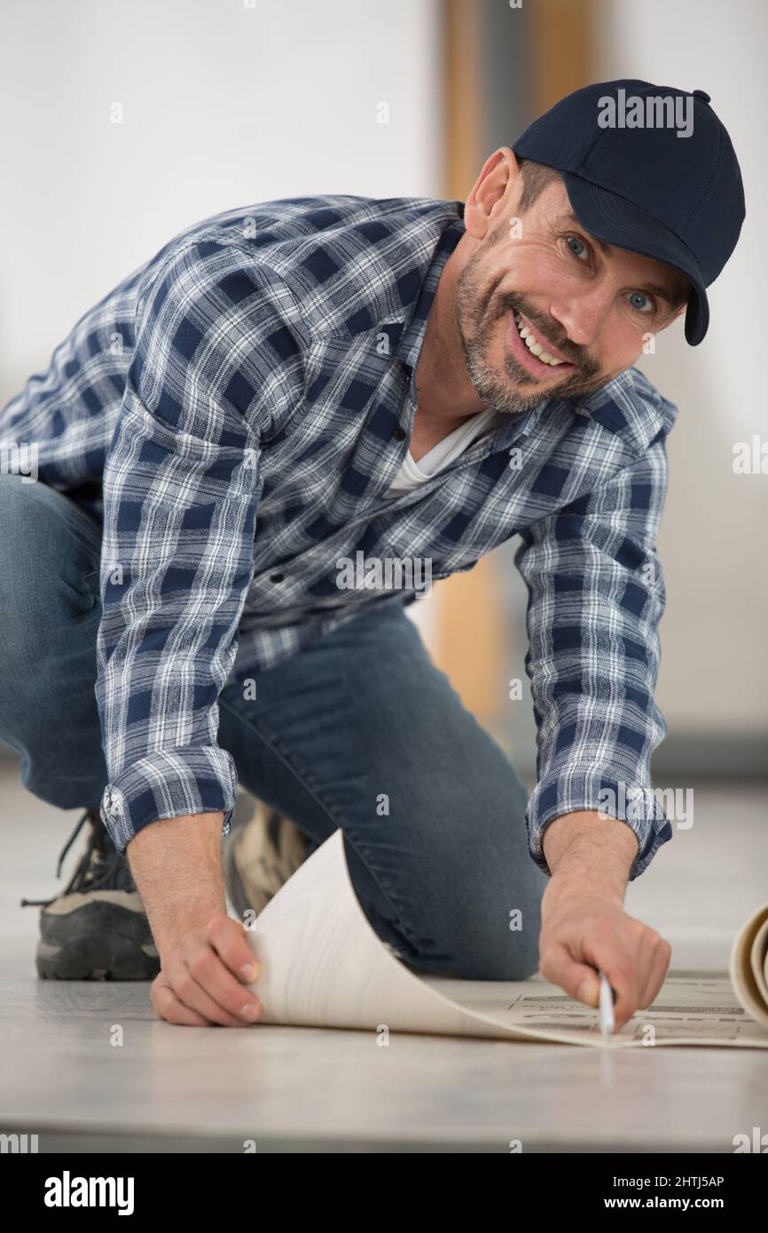 happy male worker laying carpet Stock Photo - Alamy