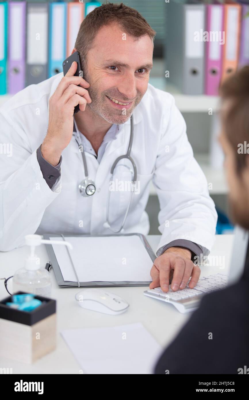 male doctor using telephone during consultation with patient Stock ...