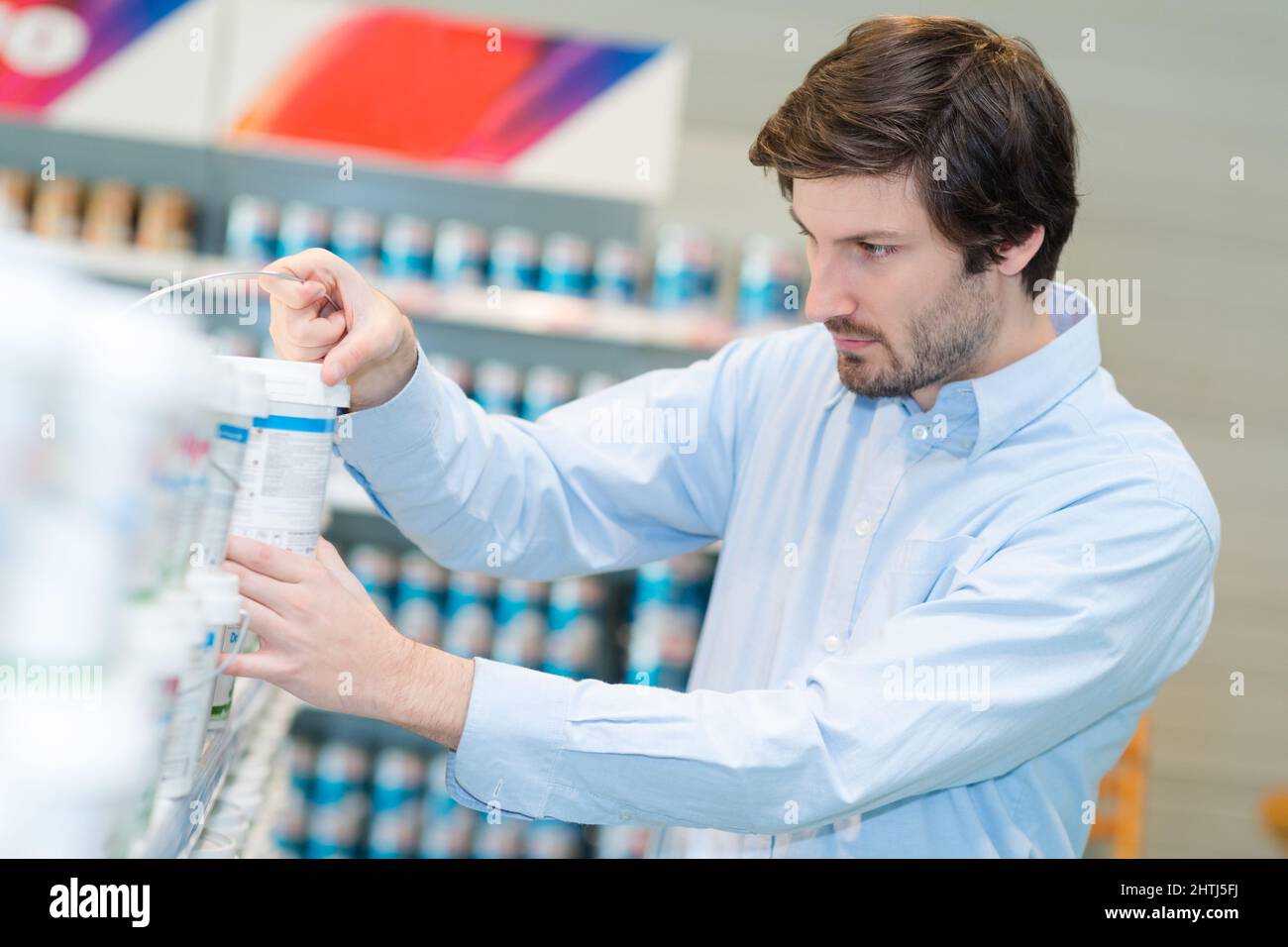 man choosing paint color at hardware store Stock Photo - Alamy