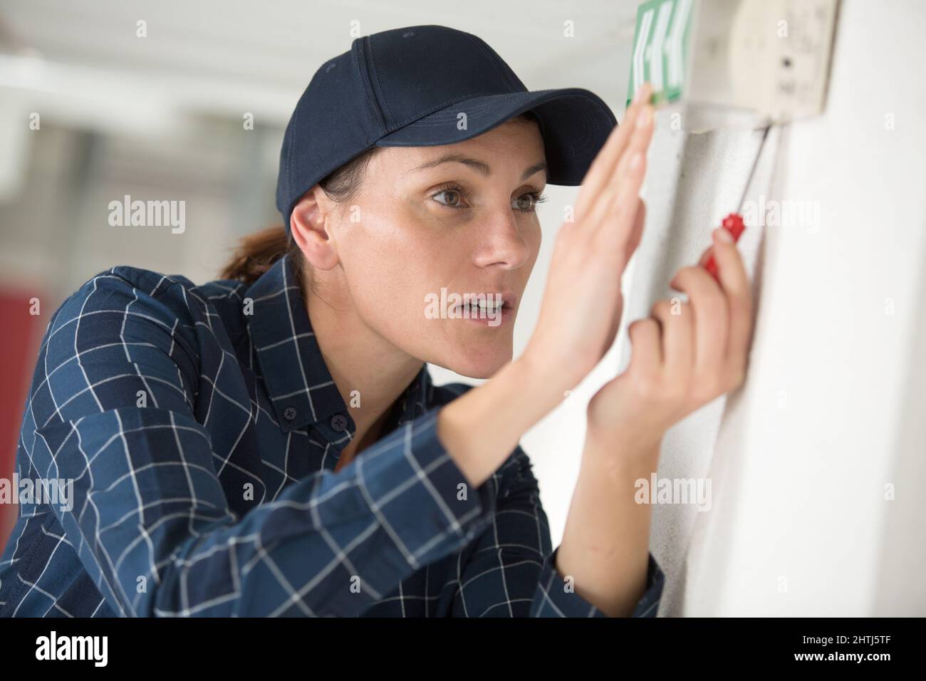 female contractor installing an exit sign Stock Photo - Alamy