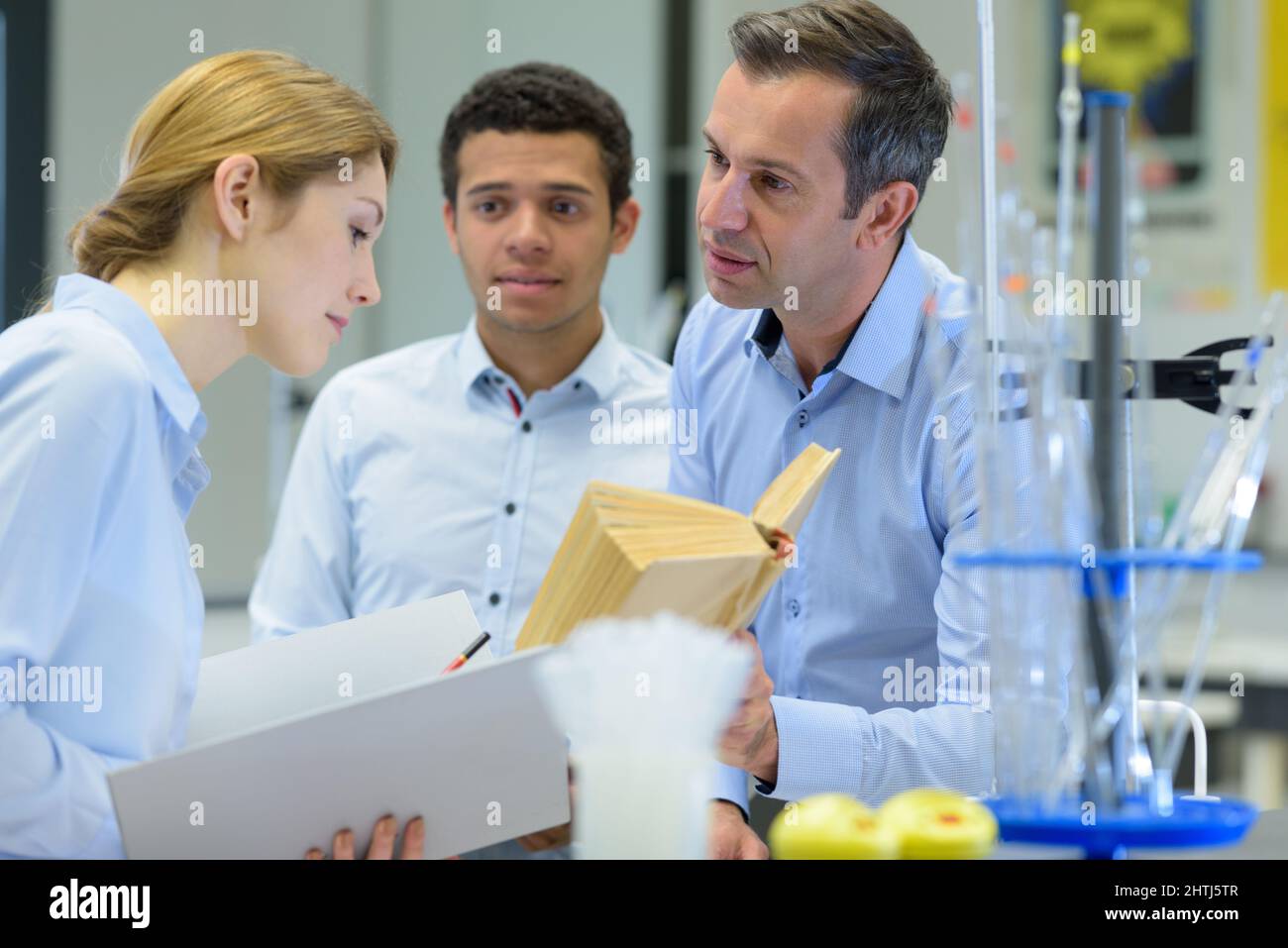 teacher showing book to student documenting science experiment Stock ...