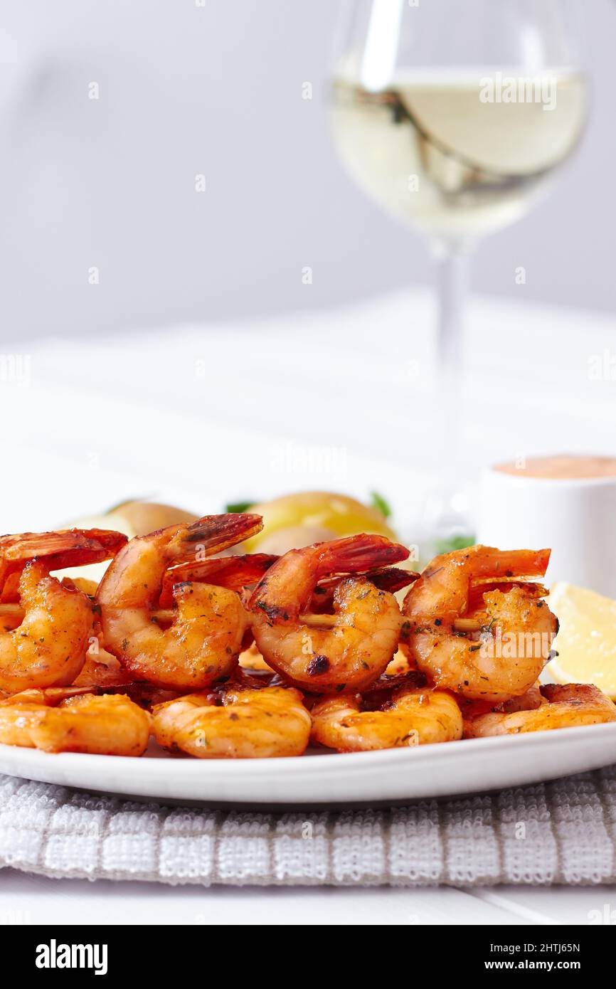 Closeup of a roasted peel prawn in white plate served with a white wine ...