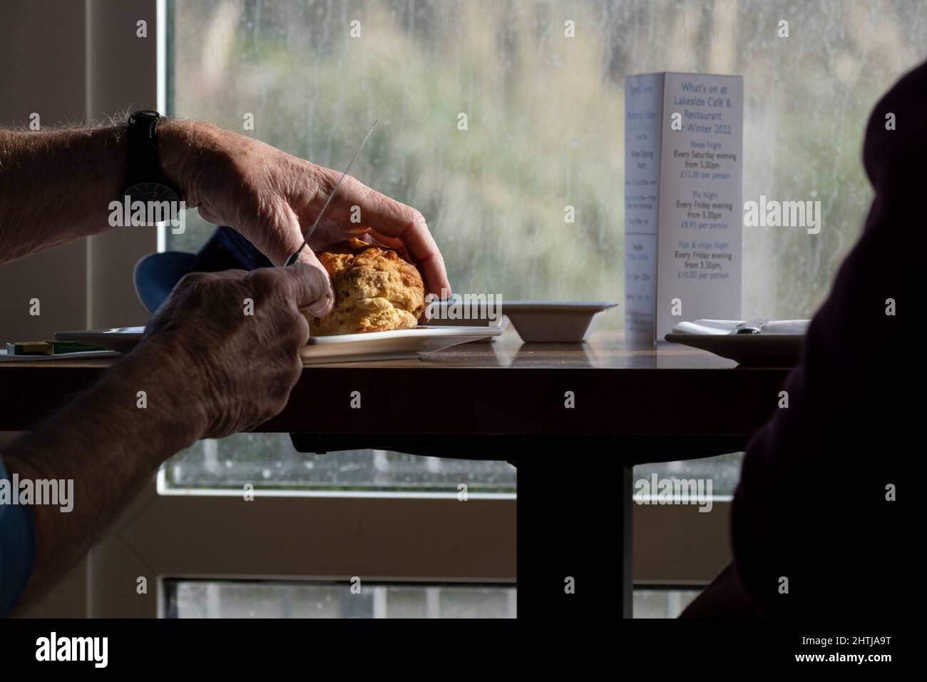 A customer cutting a scone with a knife inside a restaurant Stock Photo ...