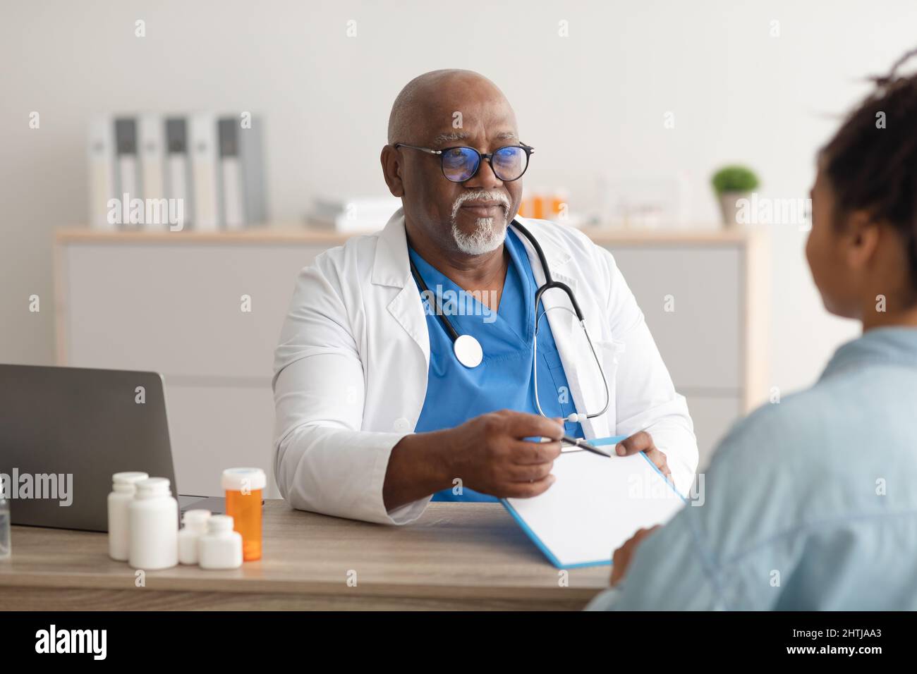 Experienced black doctor explaining treatment plan to female patient ...