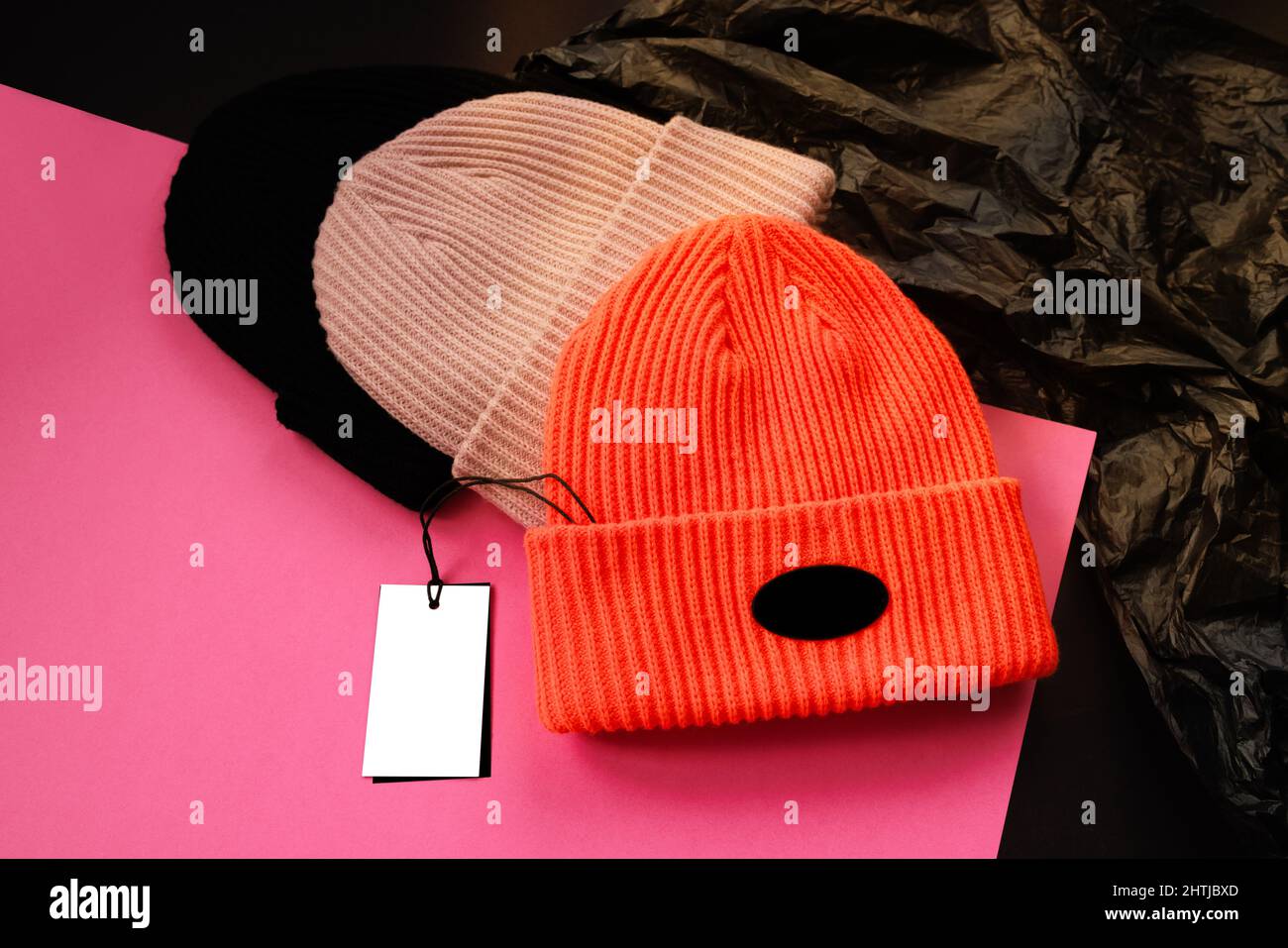 Collection of three hats in different colors with tags on bright ...