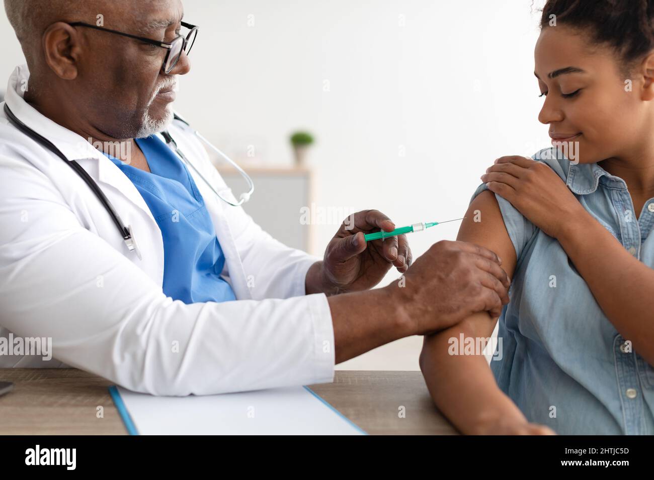 Black Woman Receiving Vaccine Injection Sitting With Doctor Indoor ...