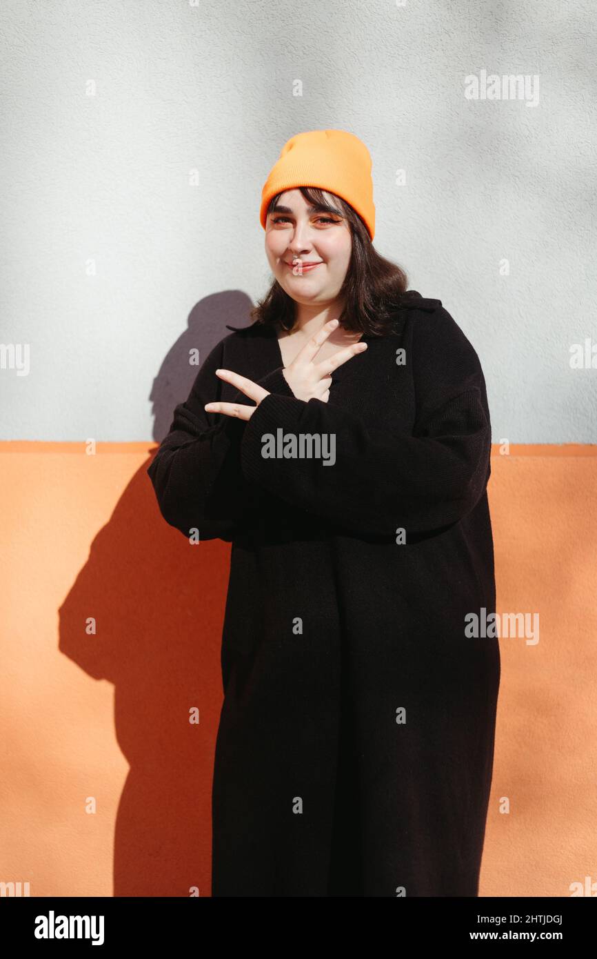 Positive young female in colorful hay showing peace gesture while ...