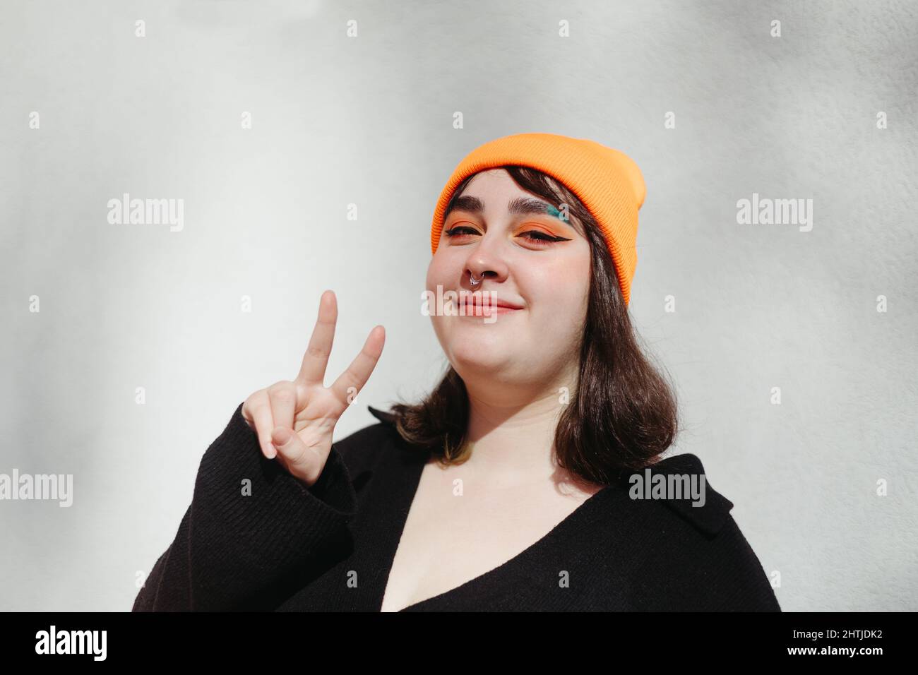 Positive young female in colorful hay showing peace gesture while ...