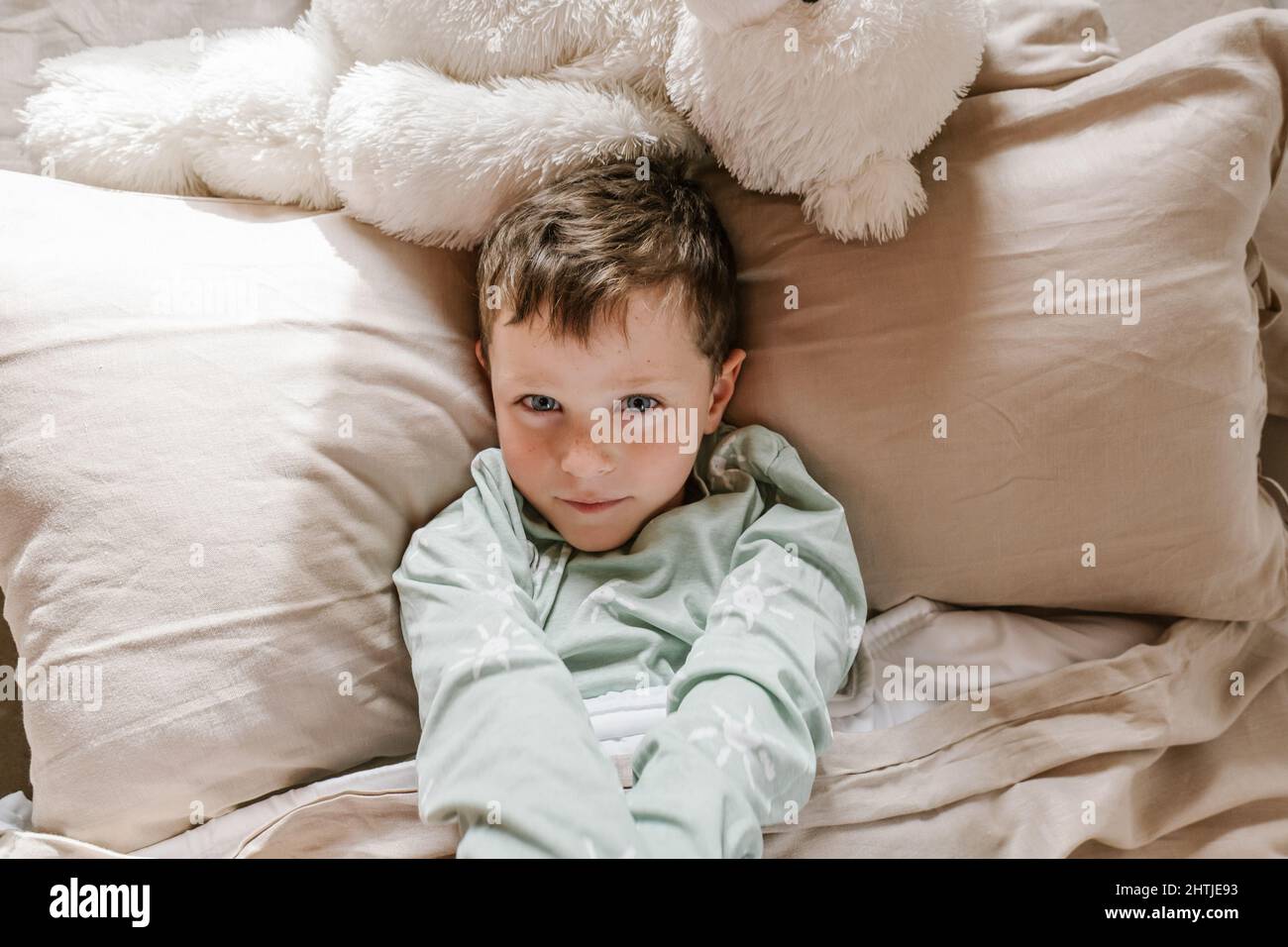 From above boy in pajama looking away while lying down on comfortable ...