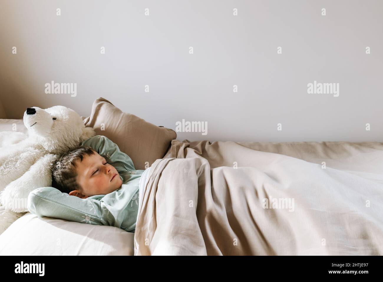 Side view of boy in pajama eyes closed while lying down on comfortable ...